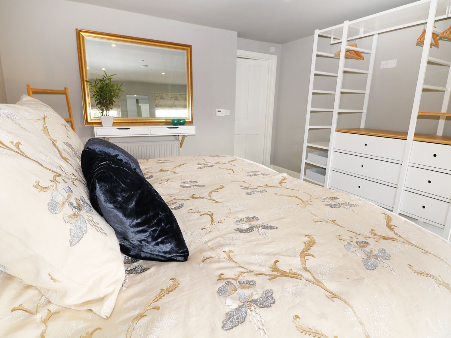 Quarto com cama, penteadeira, espelho e radiador.