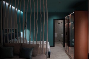 Quarto moderno com cama, sofá e closet envidraçado.
