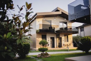 Uma casa moderna de dois andares com varanda, um pequeno jardim e área de pátio.