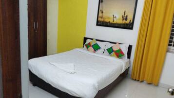 Um quarto com uma cama, uma parede amarela, um guarda-roupa de madeira e um quadro na parede.