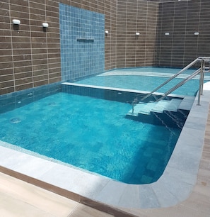 Piscina com parede revestida e escada de metal.