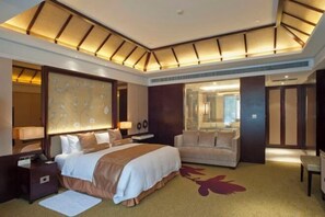 Quarto de hotel com uma cama grande, um sofá, uma escrivaninha e um espelho.