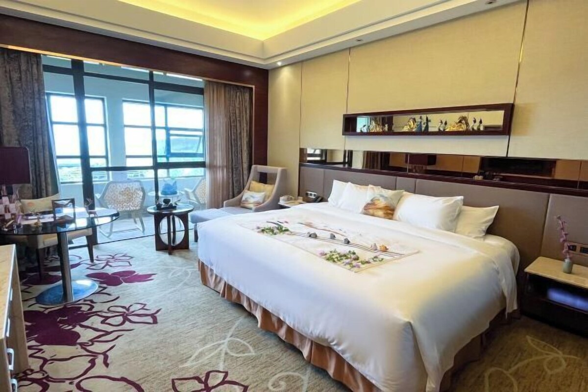 Quarto de hotel com uma cama grande, uma escrivaninha, uma cadeira e vista para o exterior.