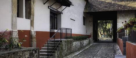 Ruas de paralelepípedos levando a um edifício com fachada branca e base vermelha.