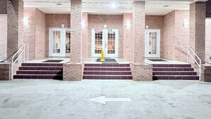 Um espaço amplo e coberto, com paredes de tijolo, portas brancas e chão de concreto com setas indicativas.