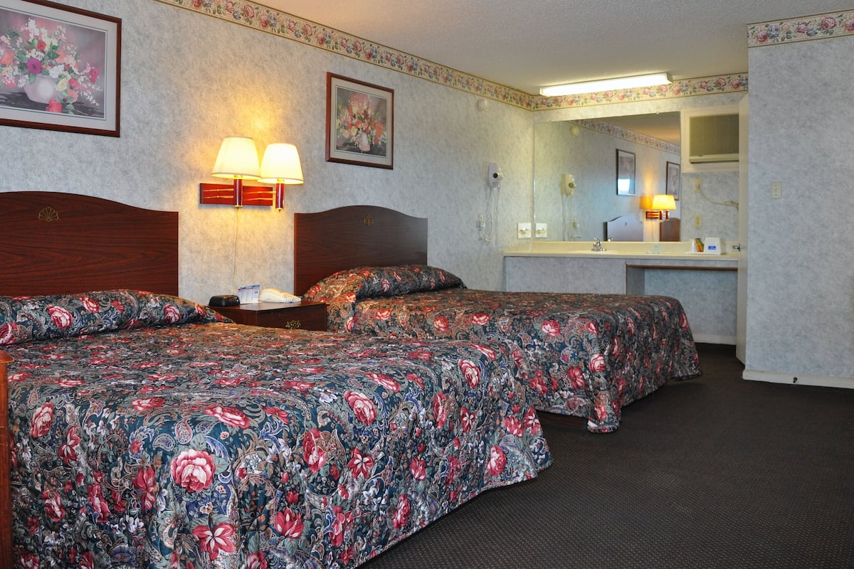 Quarto de hotel com duas camas, banheiro e uma pequena escrivaninha.