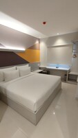 Quarto moderno com uma cama grande, mesa de cabeceira, escrivaninha e espelho.