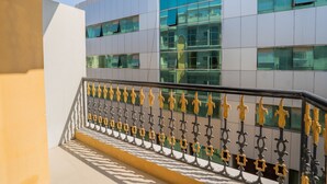 Um edifício moderno com uma escadaria, adornada com grades de metal ornamentadas e um corrimão em azulejos amarelos.