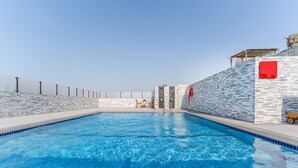 Piscina com parede de pedra e uma bandeira vermelha no lado direito.