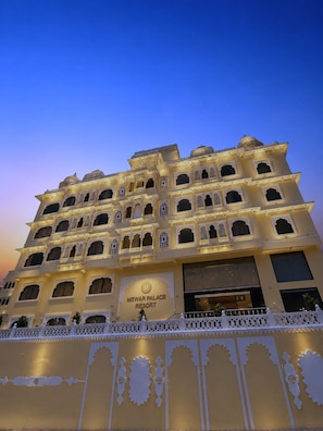 Um edifício de vários andares com uma placa que diz 'Mewar Palace Resort'.