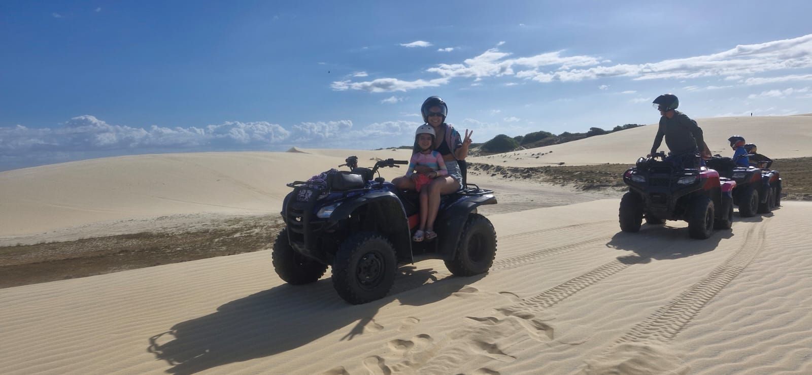 Paisagem desértica com dunas de areia e veículos.