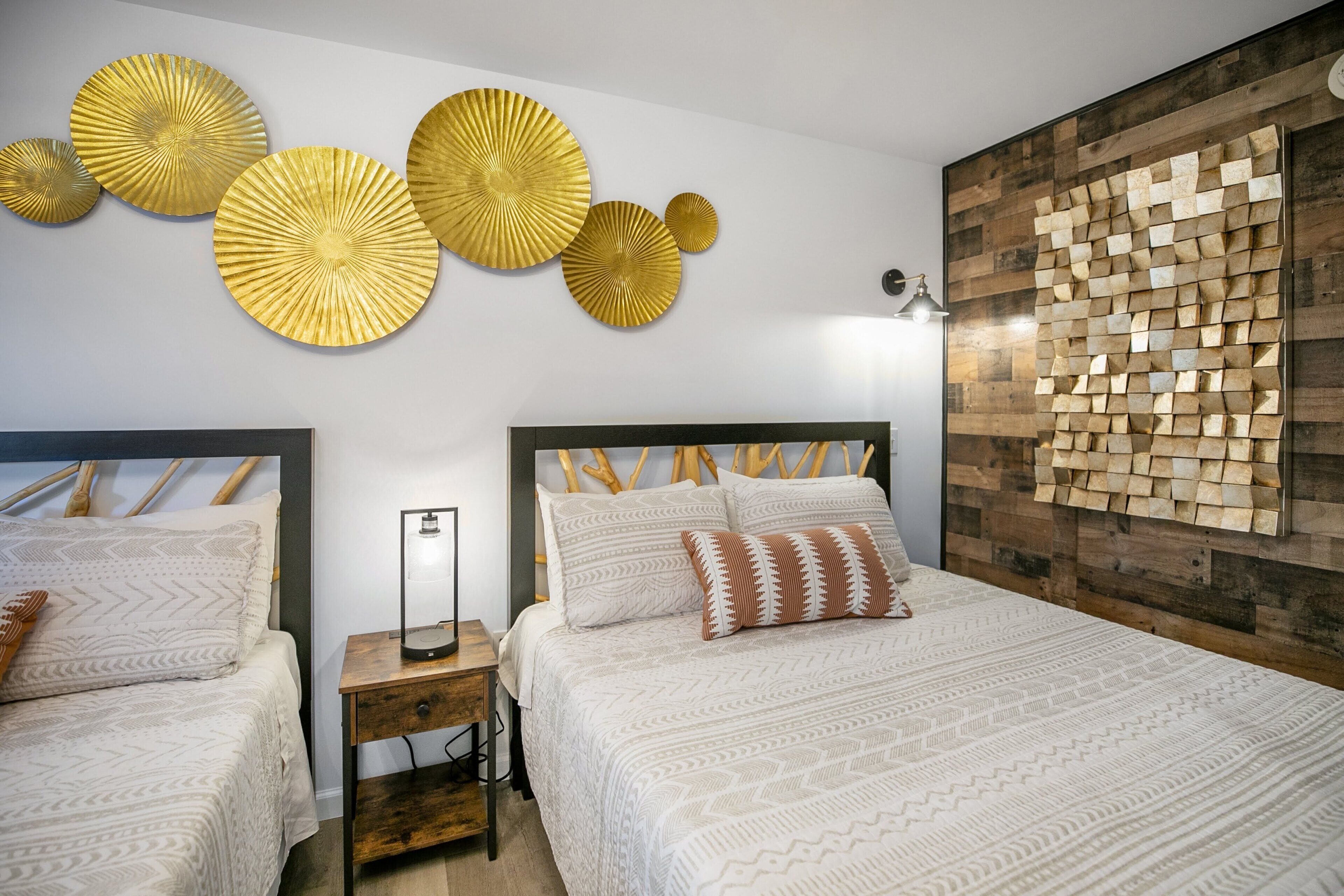Quarto com duas camas, uma mesinha de cabeceira e decoração nas paredes.