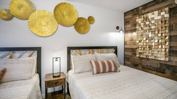 Quarto com duas camas, uma mesinha de cabeceira e decoração nas paredes.