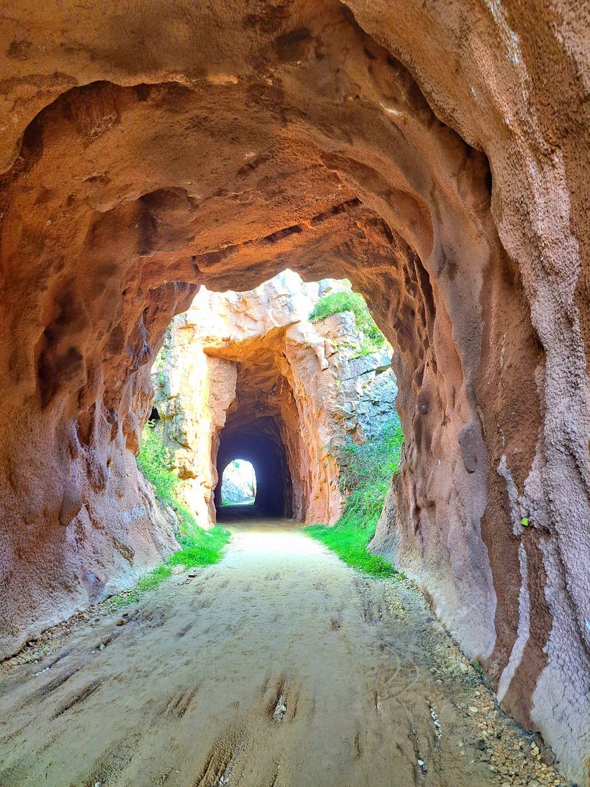 Um arco de pedra natural que dá acesso a uma túnel.