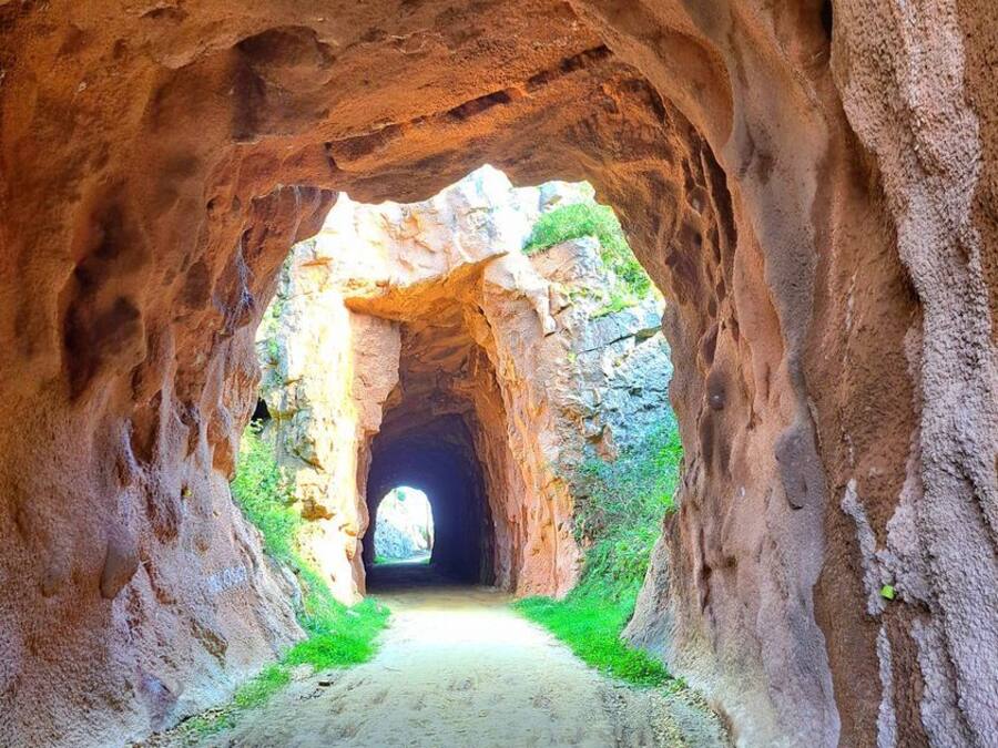 Um arco de pedra natural que dá acesso a uma túnel.