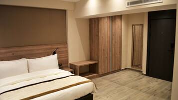 Quarto com cama, guarda-roupa de madeira e porta.