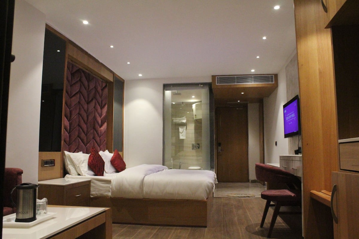 Quarto de hotel moderno com cama, mesa de cabeceira e televisão.