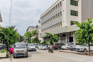 Rua com carros estacionados e um edifício de design moderno.