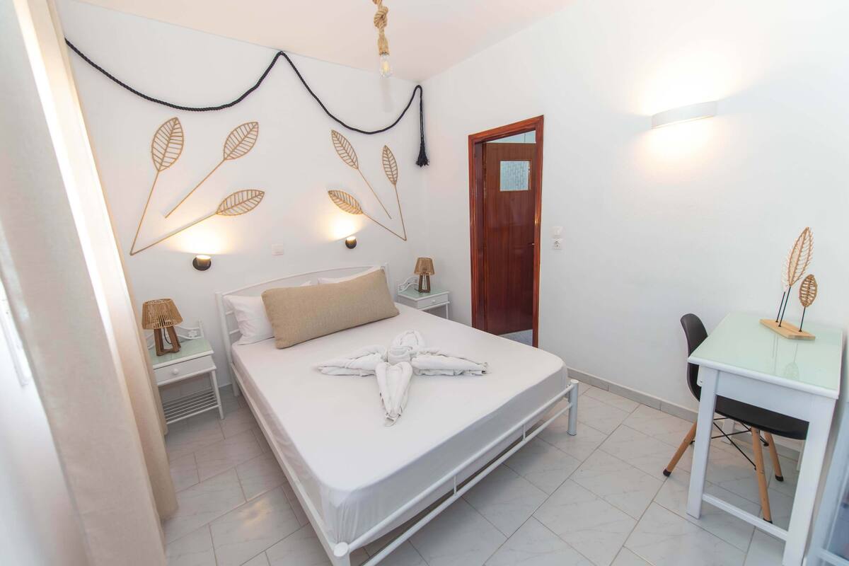 Um quarto com uma cama, mesas de cabeceira, uma escrivaninha e uma cadeira.