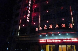 Um edifício com sinalização iluminada em vermelho, indicando um hotel ou estabelecimento similar.