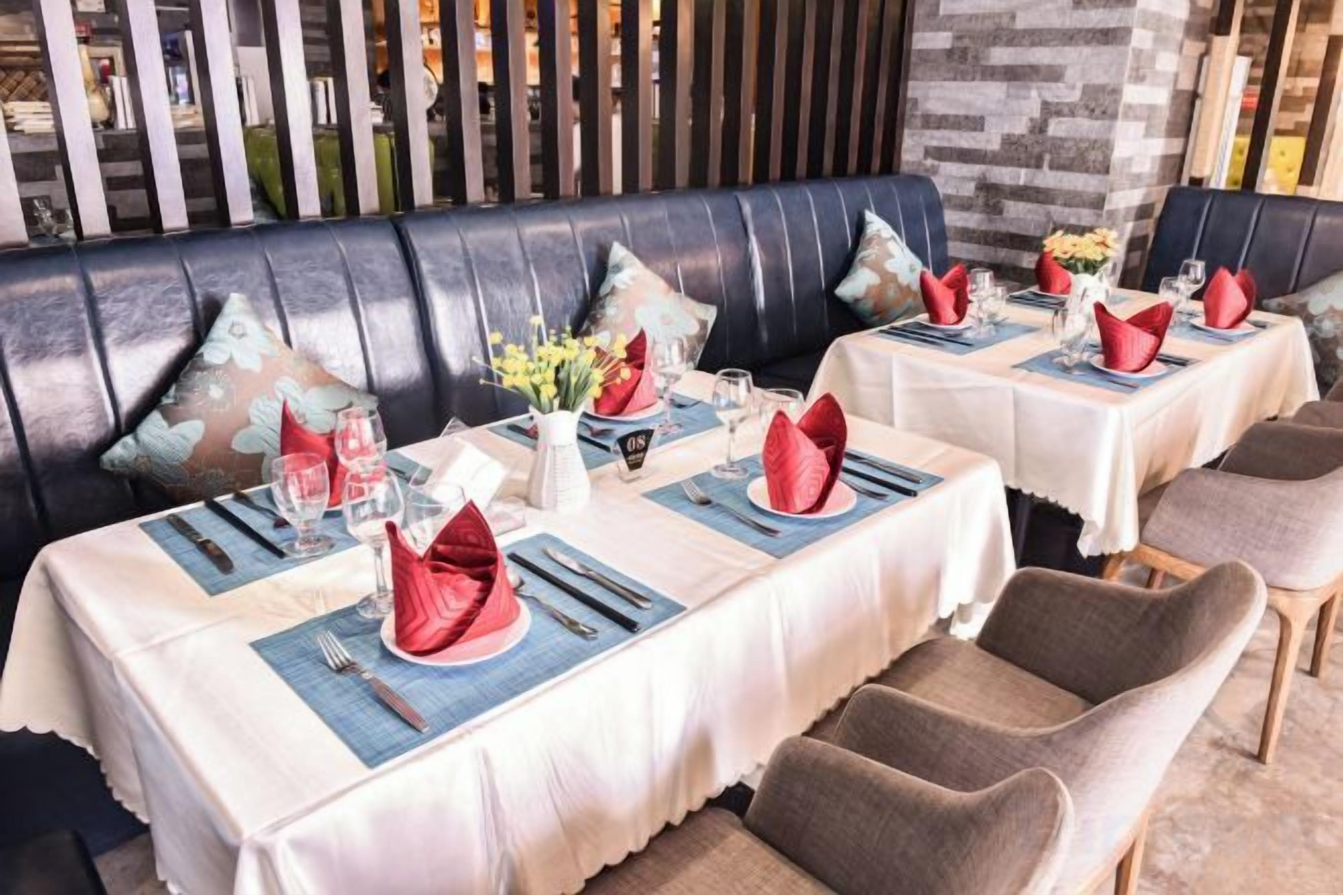 Restaurante com mesas preparadas para refeições, incluindo uma área com assentos em cabine e um bar.