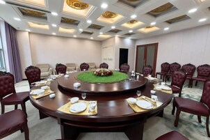 Sala de conferência com uma mesa redonda, cadeiras e piso coberto por carpete.