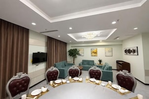 Uma sala de conferências com uma mesa redonda, cadeiras e uma televisão na parede.