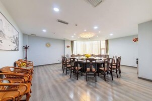 Uma sala de jantar espaçosa com uma mesa redonda e cadeiras, piso de madeira e teto com iluminação embutida.
