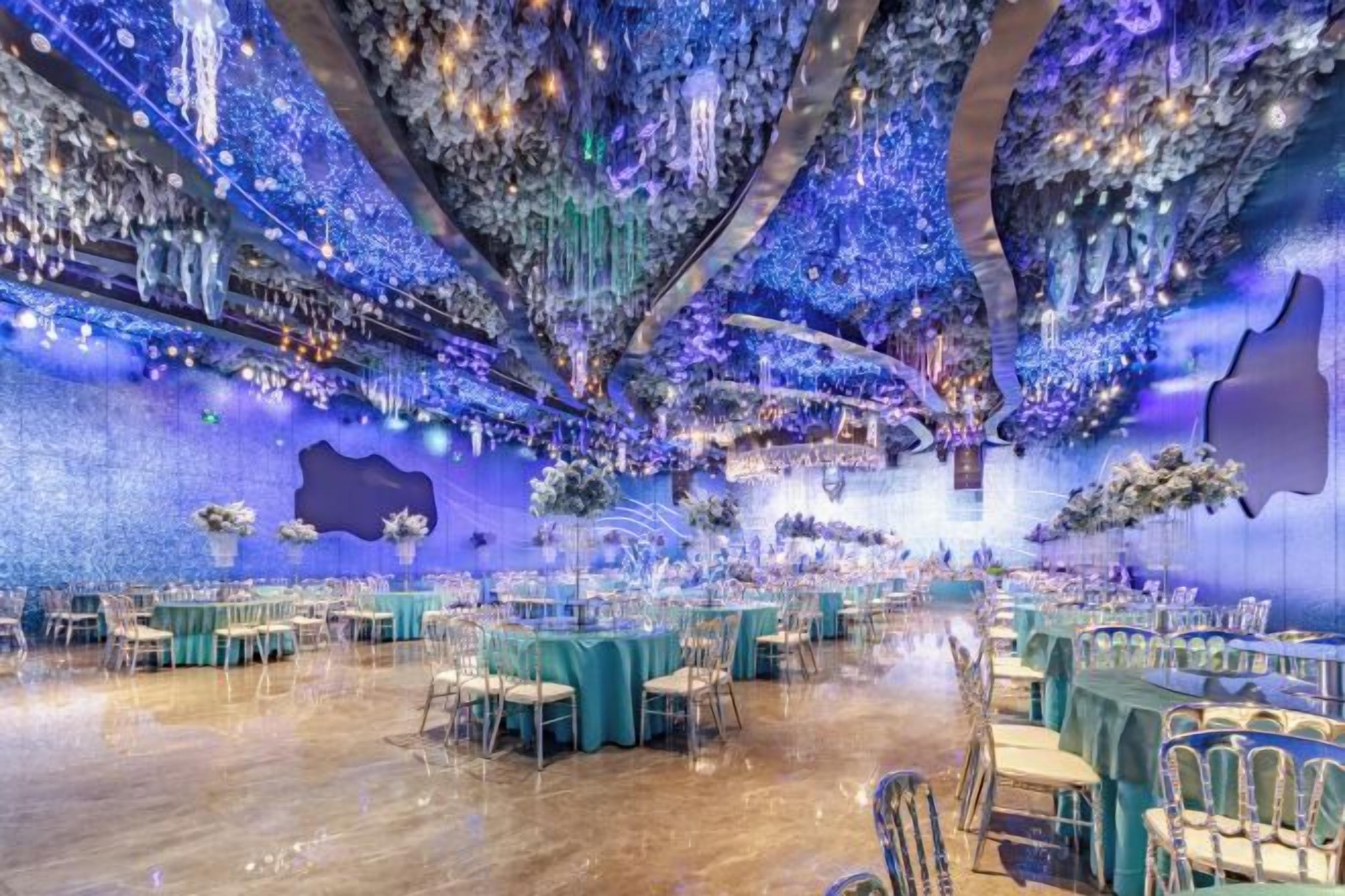 Uma sala de banquetes com mesas redondas, cadeiras e um candelabro.