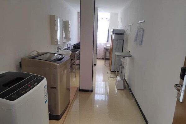 Um corredor estreito com uma área de cozinha à esquerda, com máquina de café, pia e geladeira.