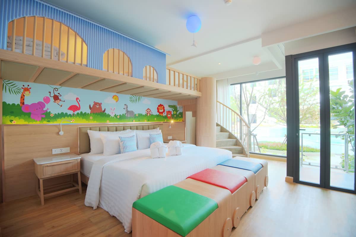 Quarto de hotel moderno com uma cama grande, um banco de madeira, um mural e uma escada que dá para uma varanda.