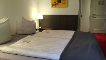 Quarto de hotel com cama bem arrumada, luminária na mesa de cabeceira e um quadro na parede.