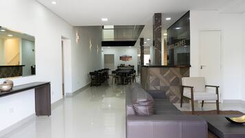 Um lobby de hotel moderno com área de refeições, balcão de recepção e um sofá.