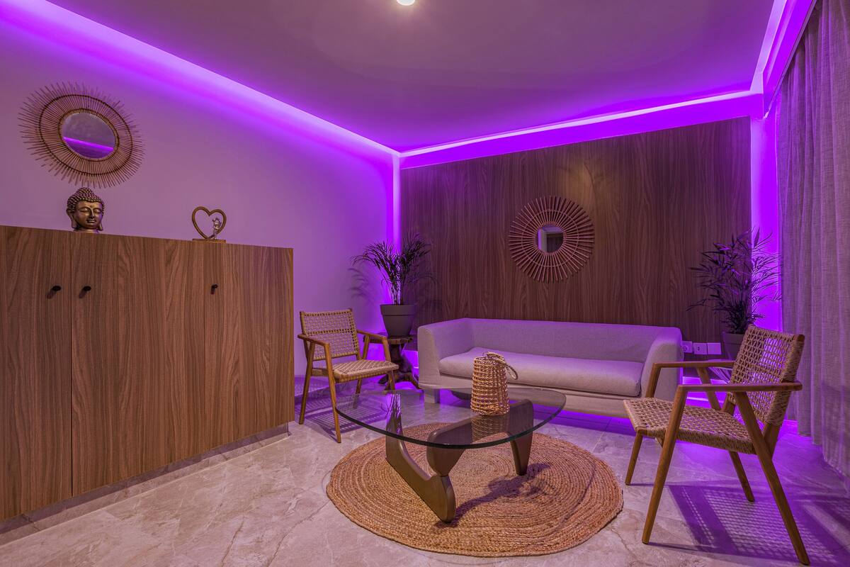 Uma sala de estar moderna com uma mesa de centro de vidro, duas cadeiras de vime, um sofá e um armário de madeira.