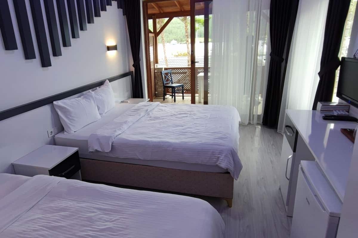 Quarto de hotel com duas camas, uma televisão e uma escrivaninha.