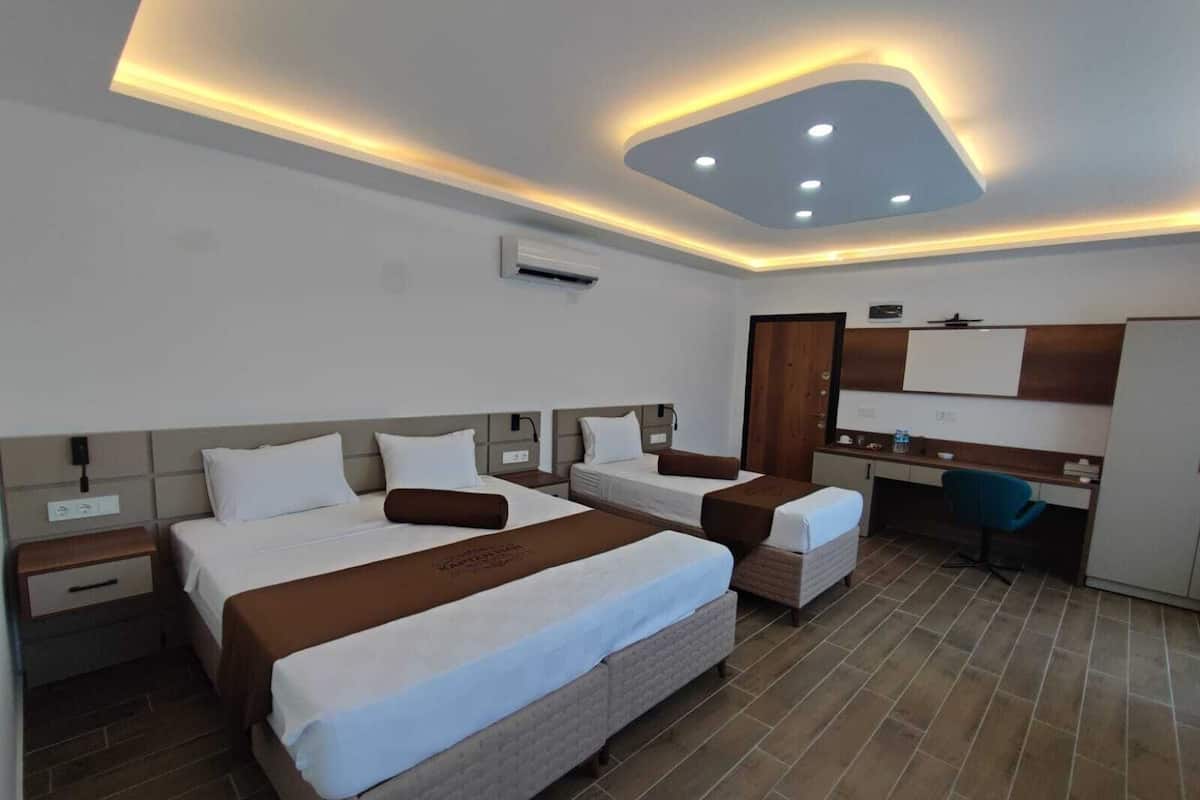 Quarto de hotel com uma cama grande, uma mesa de trabalho, uma cadeira e um pequeno espaço para sentar.