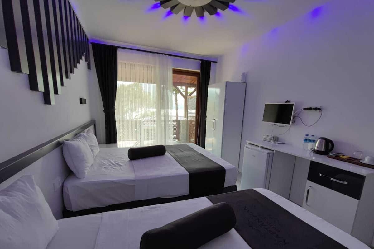 Quarto de hotel com duas camas, uma mesa com televisão, mini-geladeira e vista para o exterior.