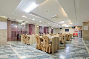 Sala de conferências com piso de mármore, diversas mesas e cadeiras.
