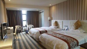 Quarto de hotel com duas camas, uma escrivaninha, uma cadeira e uma televisão.