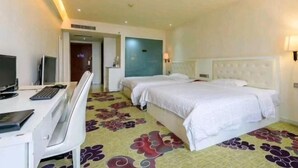 Quarto de hotel com cama, escrivaninha e computador, e uma cadeira.
