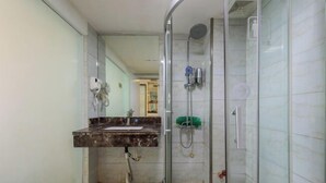 Casa de banho com cabine de chuveiro em vidro, lavatório de mármore e sanita visível.