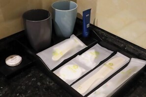 Uma bandeja com artigos de higiene pessoal, incluindo uma garrafa, dois tubos e uma embalagem azul.