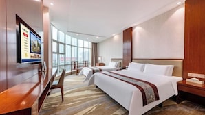 Quarto de hotel com uma cama grande, uma escrivaninha, uma cadeira e uma televisão.