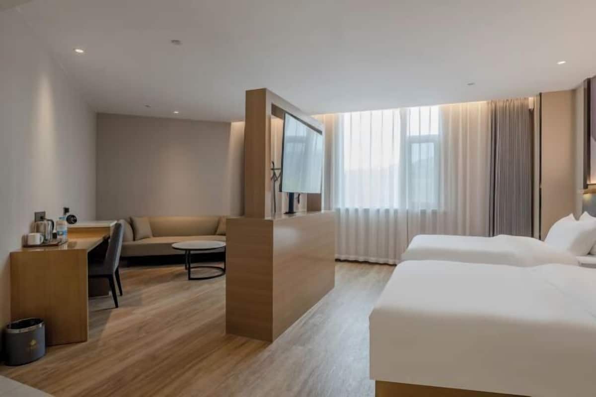Quarto de hotel com cama, escrivaninha, cadeira e sofá.