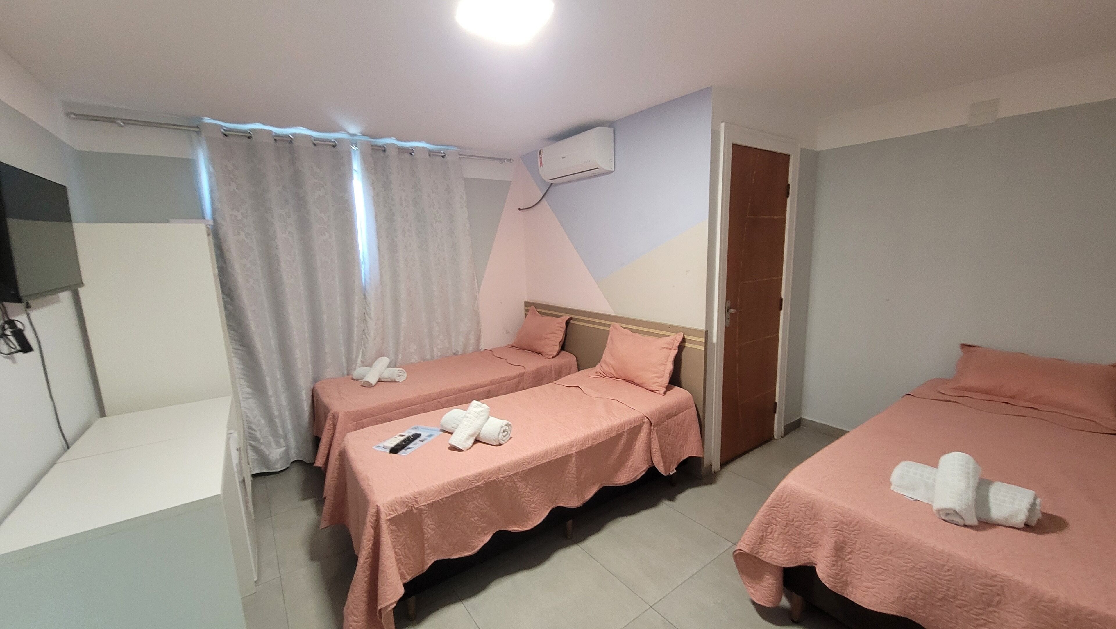 Quarto de hotel com duas camas de solteiro, banheiro e ar condicionado.