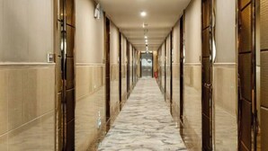 Um corredor comprido e estreito com paredes espelhadas e chão de mármore, que conduz a um ponto central.