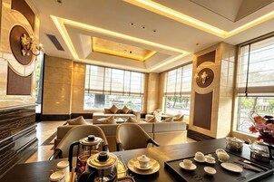 Quarto de hotel moderno com área de jantar, janelas amplas e vista para o exterior.