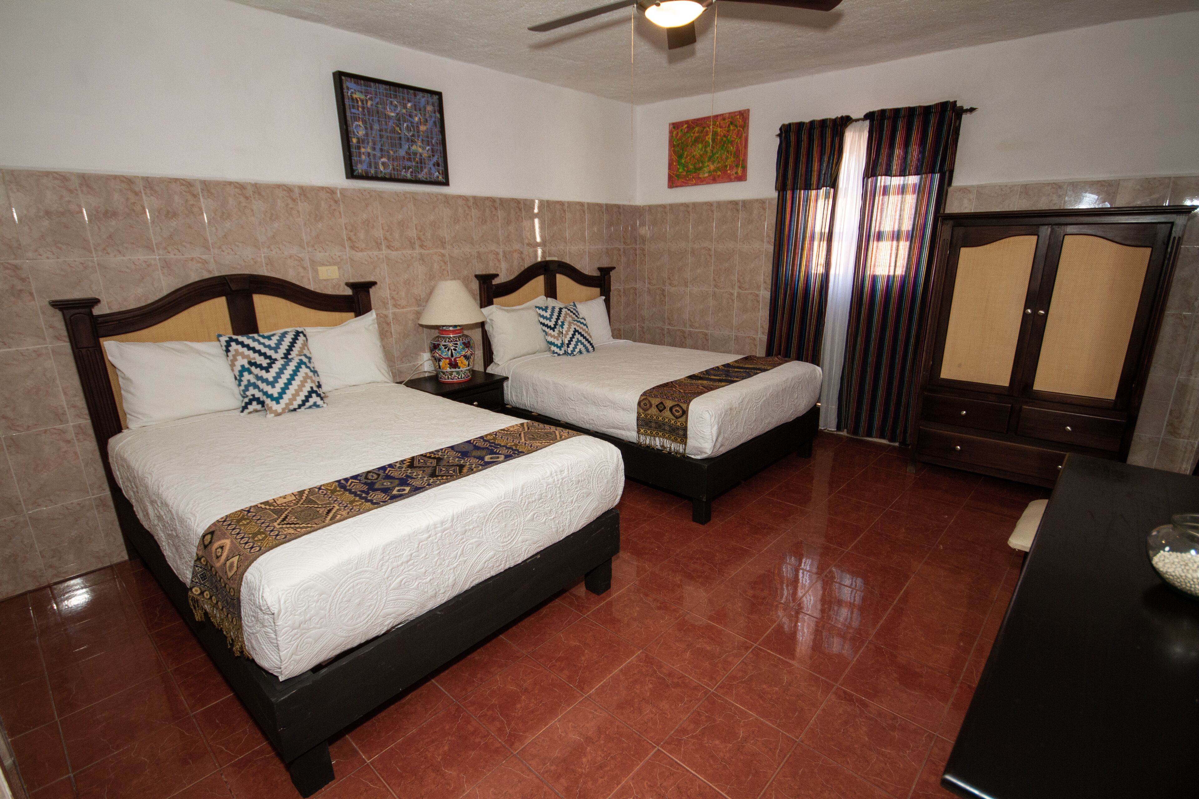 Quarto de hotel com duas camas, uma mesa de cabeceira, uma escrivaninha e um guarda-roupa.