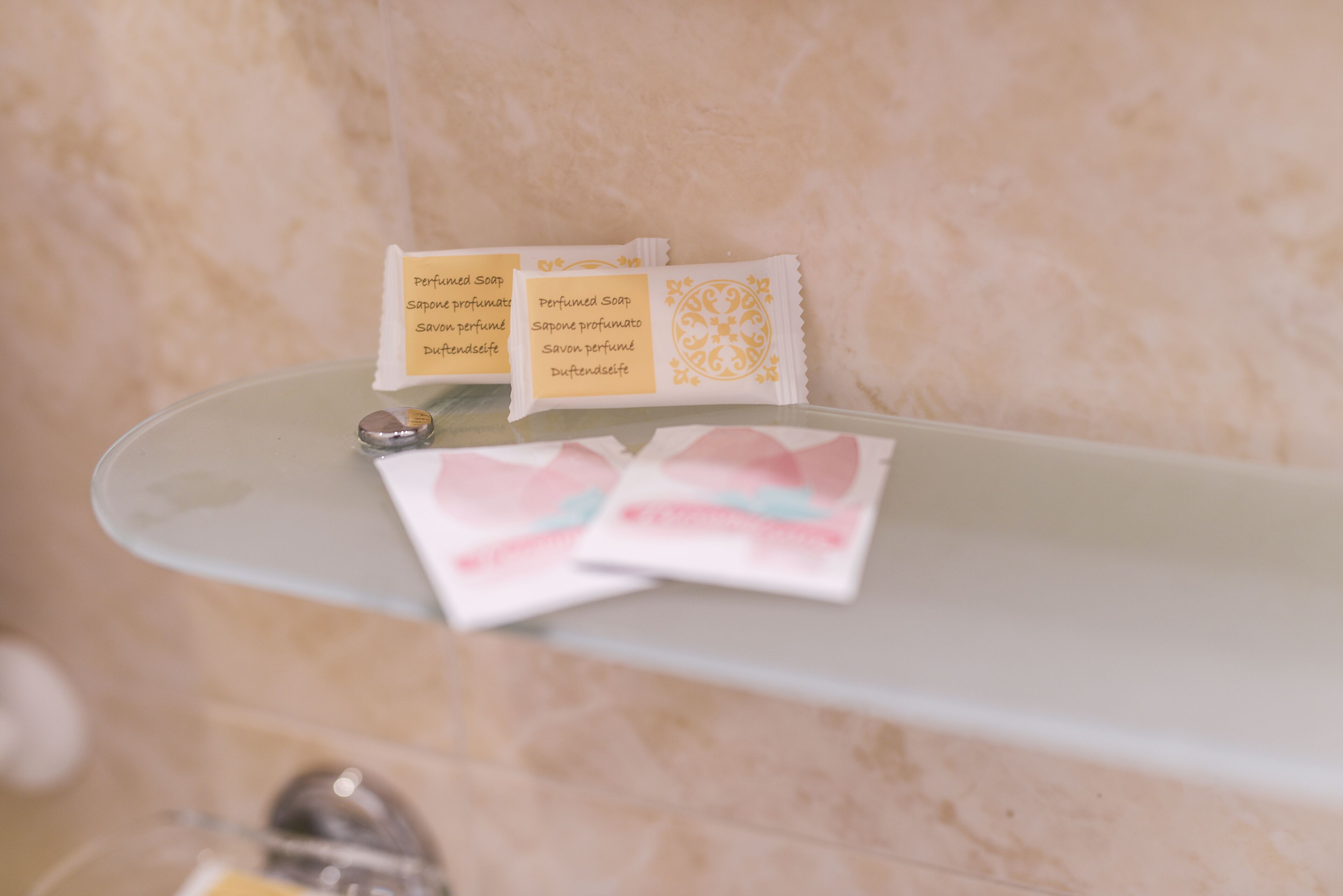 Uma prateleira no banheiro com dois pacotes de sabonete perfumado e dois pacotes menores de sabonete.