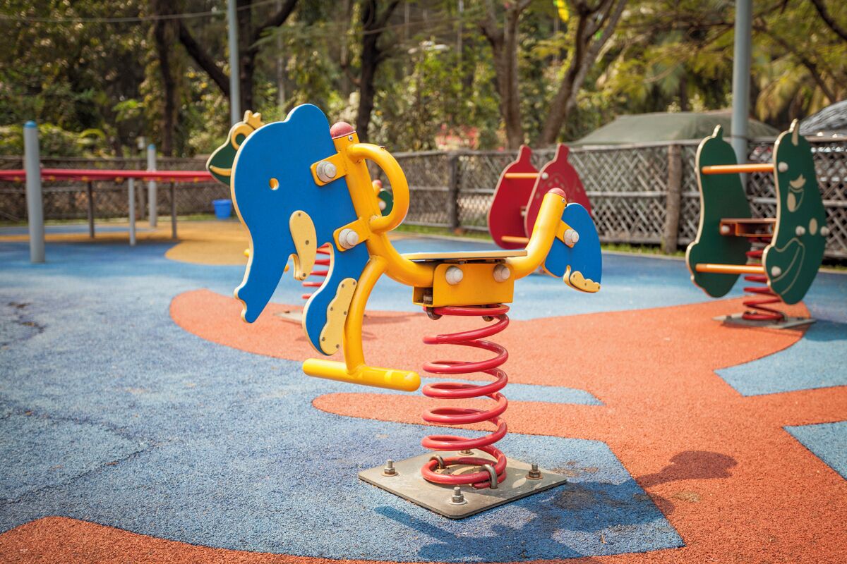 Um parquinho com equipamentos de brincadeira coloridos, incluindo um balanço e uma estrutura de escalada.